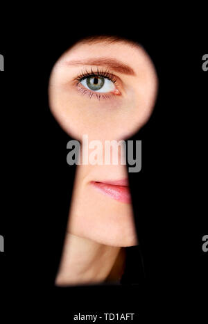 Woman looking through keyhole in light blue surface Stock Photo - Alamy