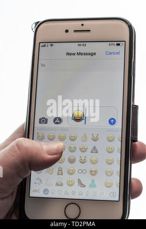 mobile phone showing someone typing the middle finger emoji, on a black ...