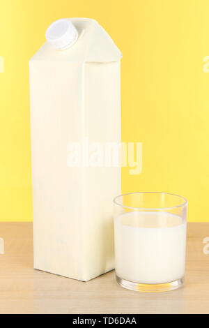 Milk pack on table on yellow background Stock Photo - Alamy