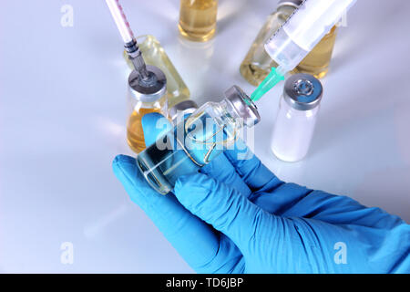 Medical bottles and syringes in hand on gray background Stock Photo - Alamy