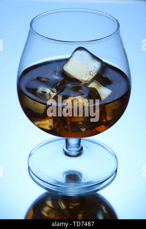 Brandy glass with ice on blue background Stock Photo - Alamy