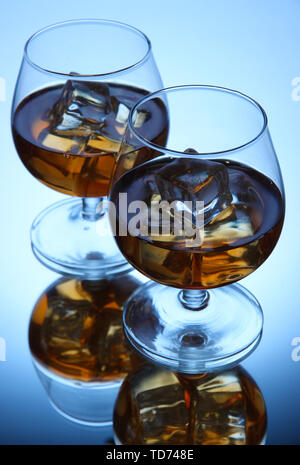 Brandy glasses with ice on blue background Stock Photo - Alamy