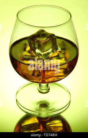 Brandy glass with ice on green background Stock Photo - Alamy