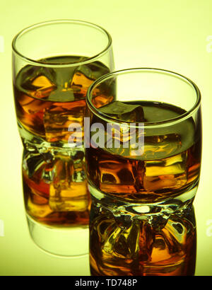 Brandy glasses with ice on green background Stock Photo - Alamy