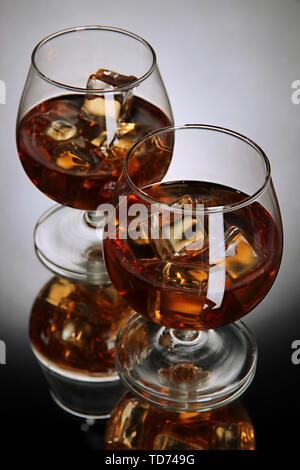 Brandy glasses with ice on grey background Stock Photo - Alamy