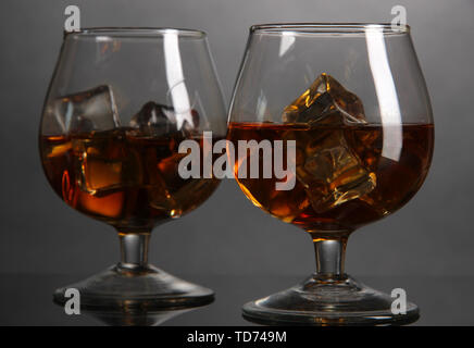 Brandy glasses with ice on grey background Stock Photo - Alamy