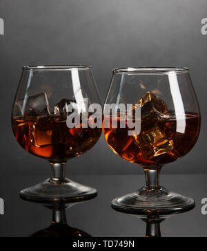 Brandy glasses with ice on grey background Stock Photo - Alamy
