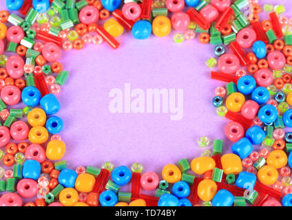 Different colorful beads on purple background Stock Photo - Alamy