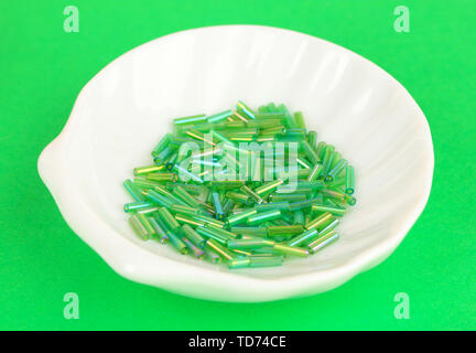Green beads on plate on green background Stock Photo - Alamy