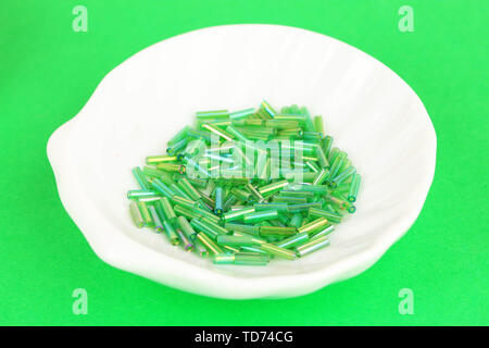 Green beads on plate on green background Stock Photo - Alamy