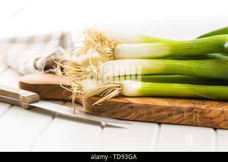 Fresh green onions on a cutting board over white wooden background ...