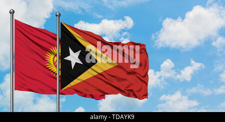 East Timor and Kyrgyzstan flag waving in the wind against white cloudy ...