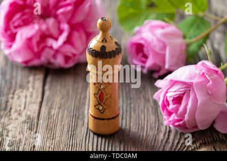A bottle of essential oil with fresh cabbage roses on a table Stock ...