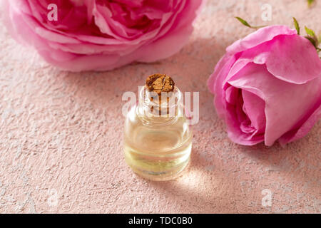A bottle of essential oil with fresh cabbage roses on a table Stock ...