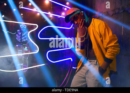 Black rapper in underpass neon lights on background. Rap performer in ...