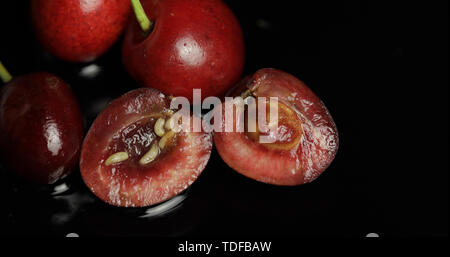 Fruit worms in rotten cherry, black background. Larva of cherry flies ...