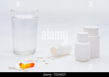 Alarm clock with pill bottles and glass of water on table in bedroom ...