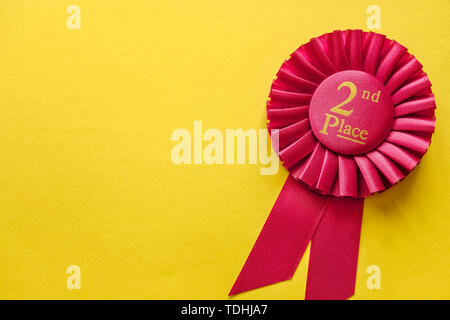 Red 2nd place ribbon rosette with gold central text in a pleated ...