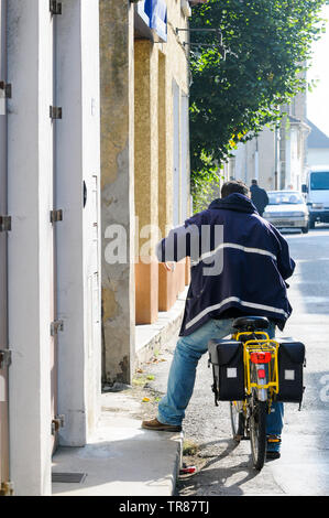 Postman with La Poste yellow bicycle with postman delivering mail in ...