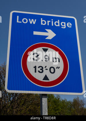 Low bridge sign indicating height restriction with damaged brickwork ...