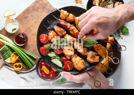 Man holding kebabs on skewers. Top view Stock Photo - Alamy