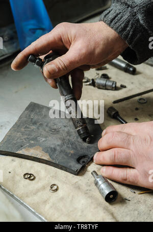 Mechanics repairing a diesel injector. Mans hands disassemble a ...
