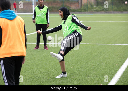 Muslim girls playing football on an astroturf training pitch. Some are ...