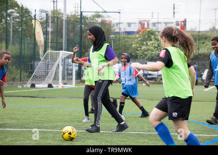 Muslim girls playing football on an astroturf training pitch. Some are ...