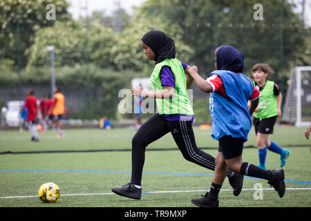 Muslim girls playing football on an astroturf training pitch. Some are ...