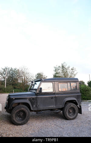 land rover defender 90 swb driving along an unmade stone track road ...