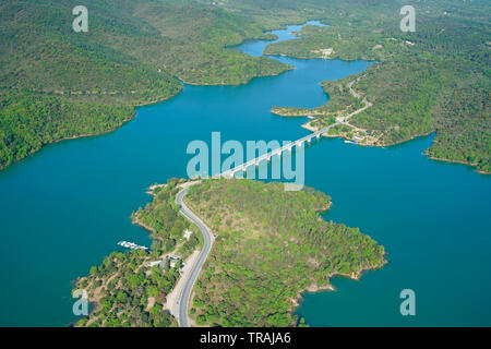 An aerial of a scenic lake surrounded by a dense forest with autumn ...