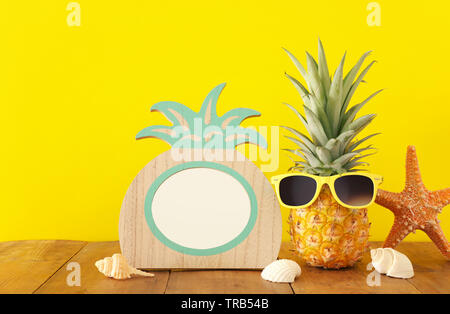 Empty photo frame and funny pineapple with sunglasses. For photography ...
