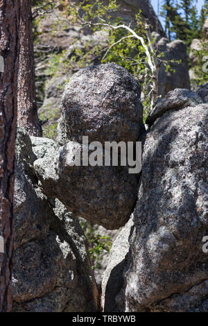 A large boulder wedged between two towering cliffs in a foggy landscape ...