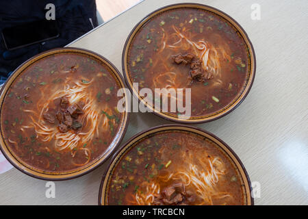 Chinese spicy beef noodle soup served with red chopsticks and chili oil ...