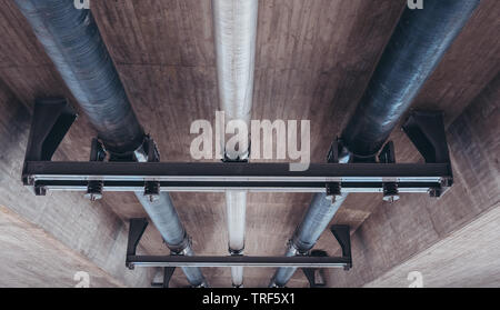 Pipe under a concrete bridge with dampers and steel support to keep it ...