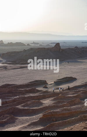 Tourists watch the sunset over yardangs, called kuluts in Iran, in the ...