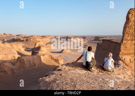 Tourists watch the sunset over yardangs, called kuluts in Iran, in the ...