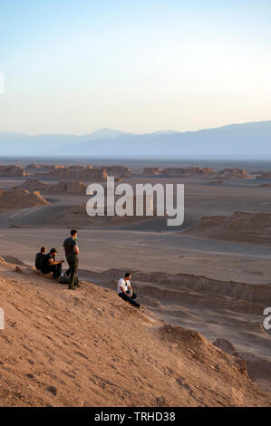 Tourists watch the sunset over yardangs, called kuluts in Iran, in the ...