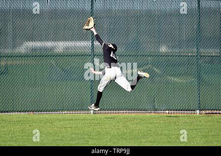 High school outfielder making a running catch to retire a hitter during ...