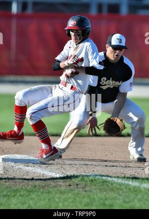 A high school baseball third baseman fielding the ball on the infield ...