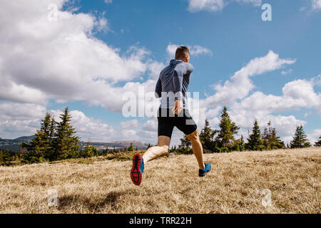 back male runner run uphill on mountain trail near the cliff Stock ...