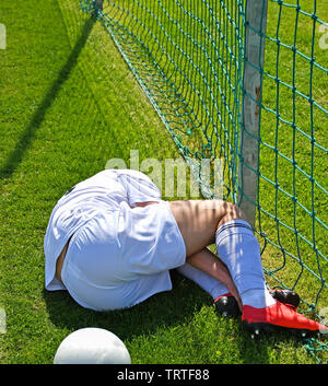 Injured young football player on bench with arm in cast from injury and ...