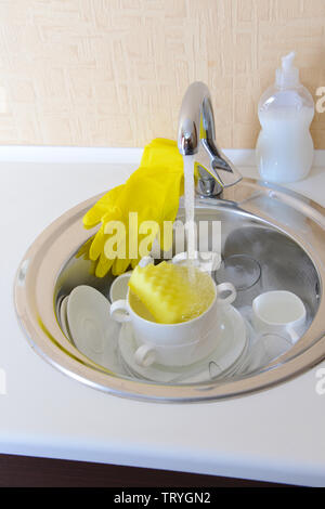 Stack of dishes soaking in kitchen sink Stock Photo - Alamy