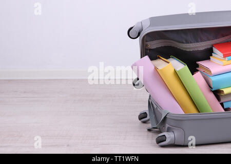 Books in suitcase on wall background Stock Photo - Alamy