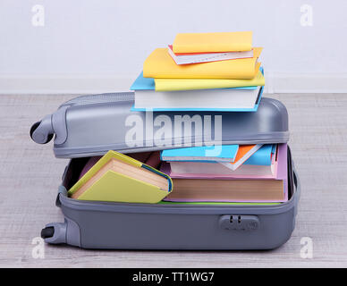 Books in suitcase on wall background Stock Photo - Alamy