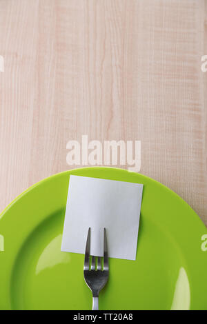 Empty note paper attached to fork, on plate, on color wooden background ...