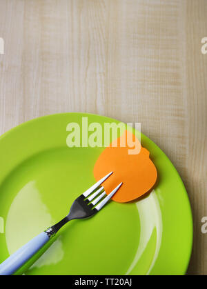 Empty note paper attached to fork, on plate, on color wooden background ...