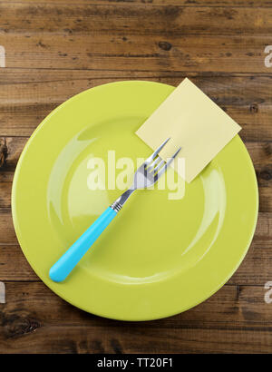 Empty note paper attached to fork, on plate, on color wooden background ...