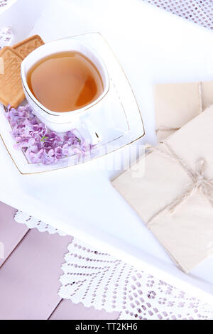 Composition with cup of tea, old letters on tray, on color wooden ...