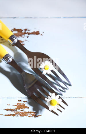 Steel forks with daisies on wooden table surface Stock Photo - Alamy